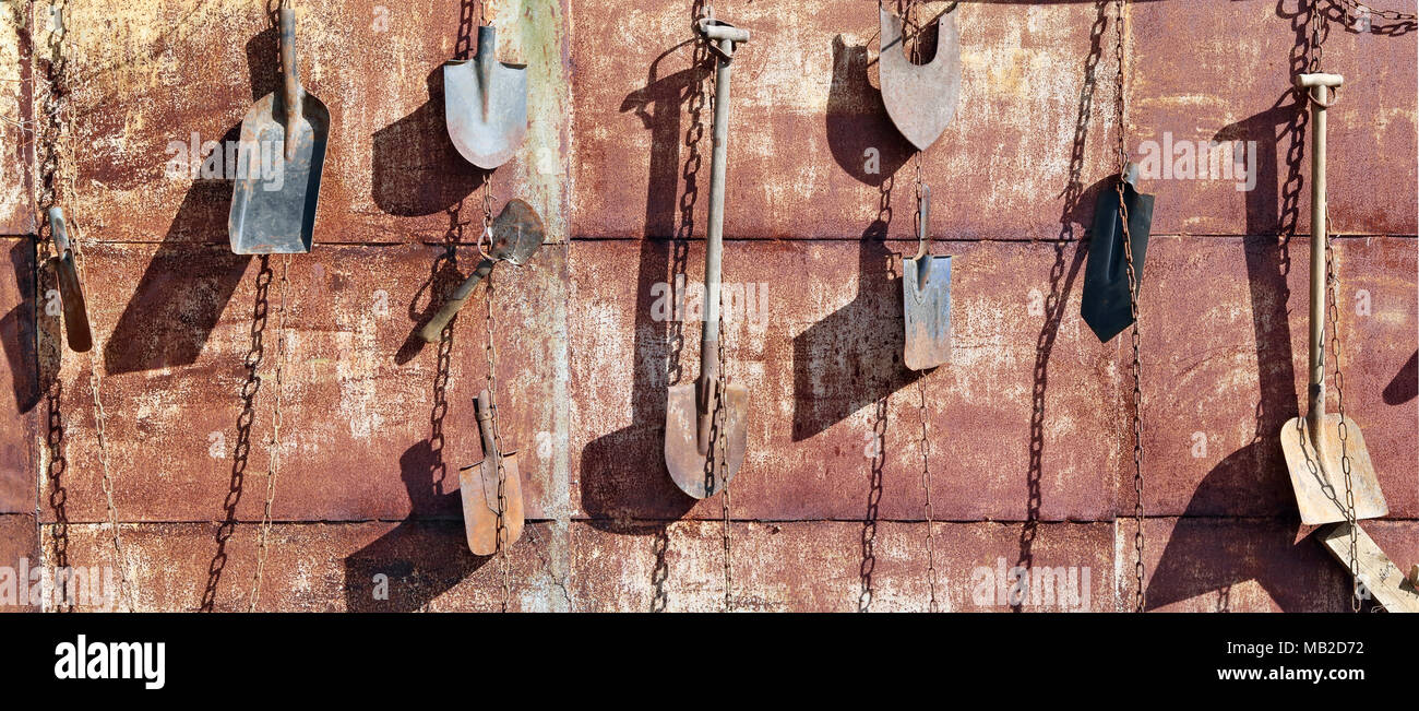 On the rusty metal wall of the village barn hang on the chains used ...