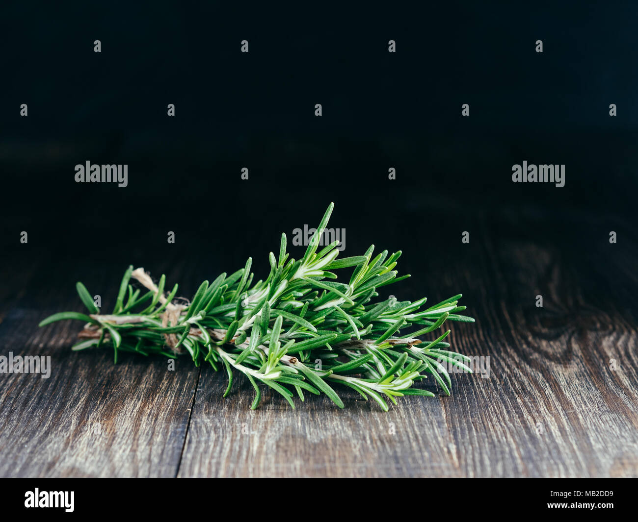 Organic bunch of fresh rosemary on wooden table with copy space. Low ...