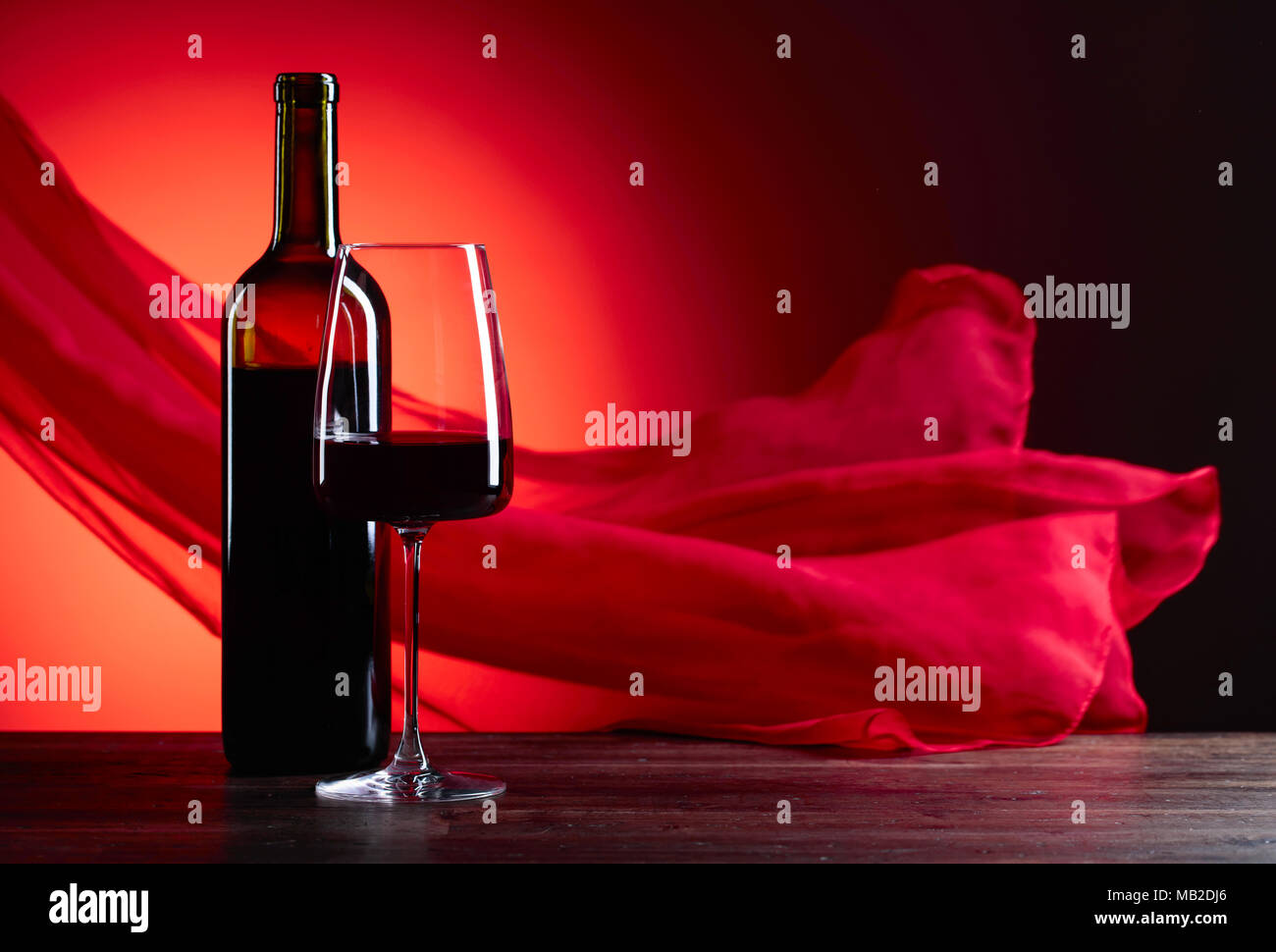 Glasses and bottle of rede wine on a red background. Red sheer fabric ...