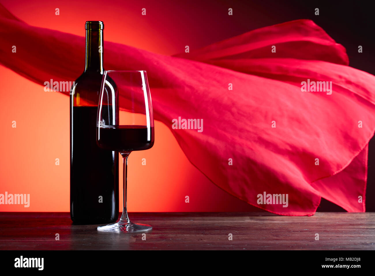 Glasses and bottle of rede wine on a red background. Red sheer fabric ...