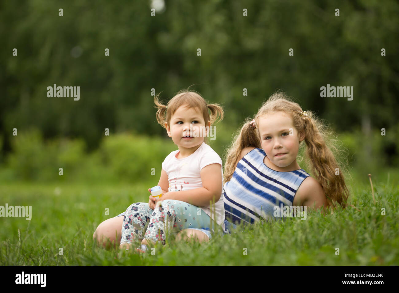 A portrait of two sisters on green grass, park outdoor Stock Photo - Alamy