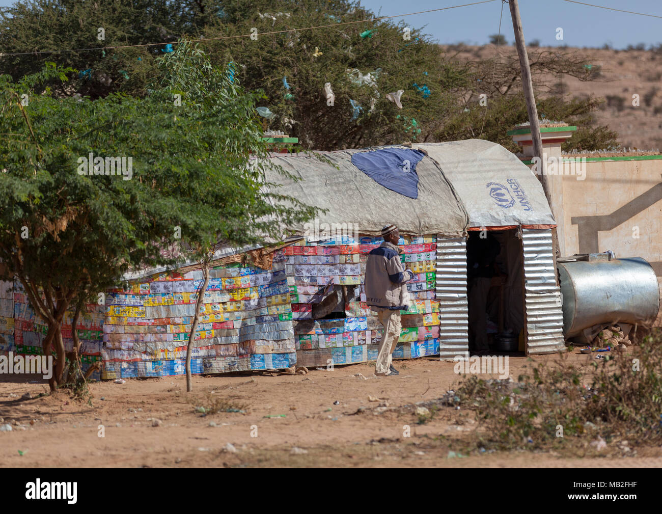 Somali man in front of a slum hut made of corrugated iron and canvas ...