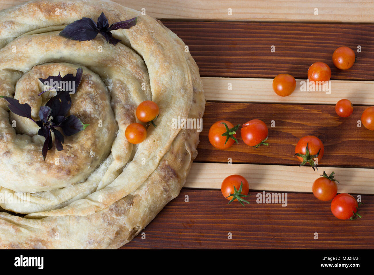 spiral filo pie burek with cherry tomatoes on wooden table Stock Photo ...