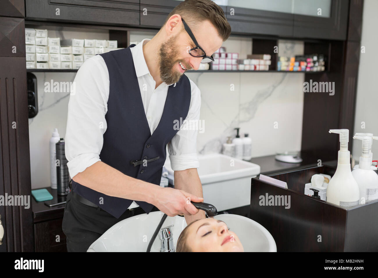 Portrait of happy hairdresser washing customer head Stock Photo - Alamy