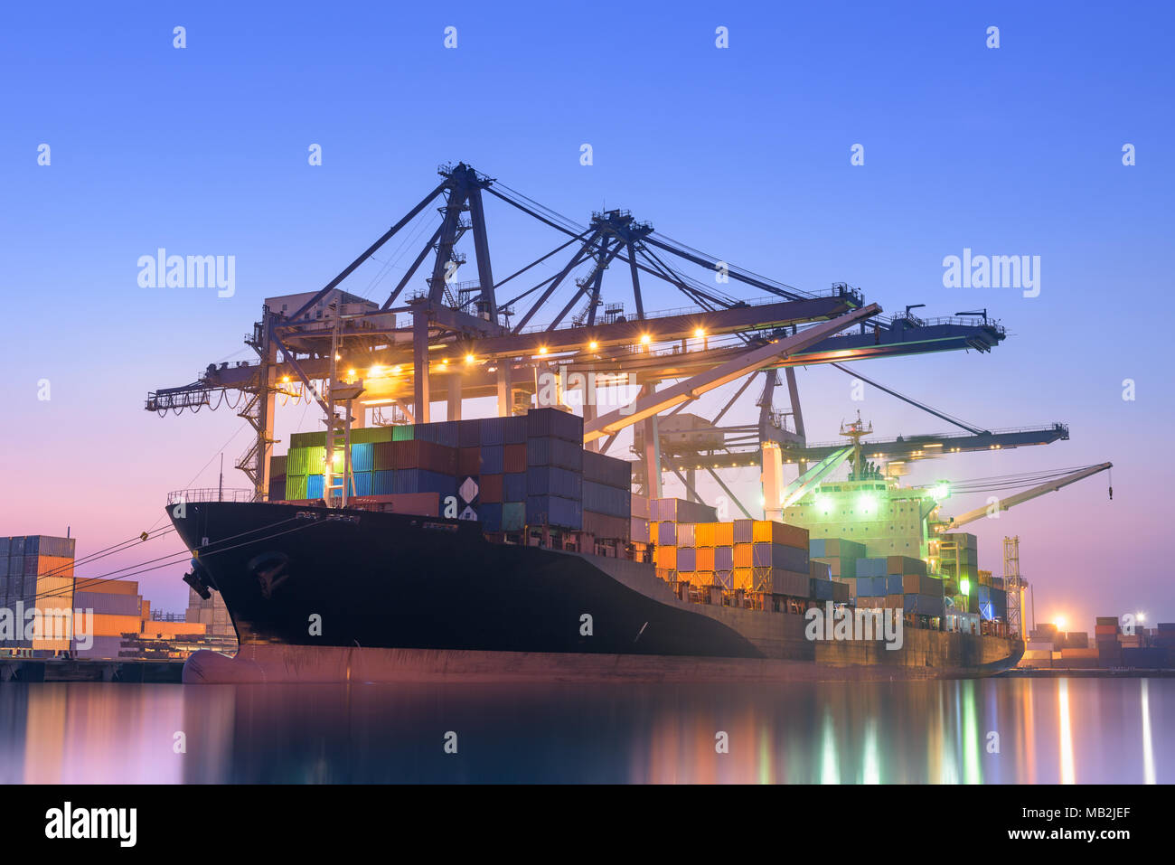 Cargo ship unloading container at twilight Stock Photo - Alamy