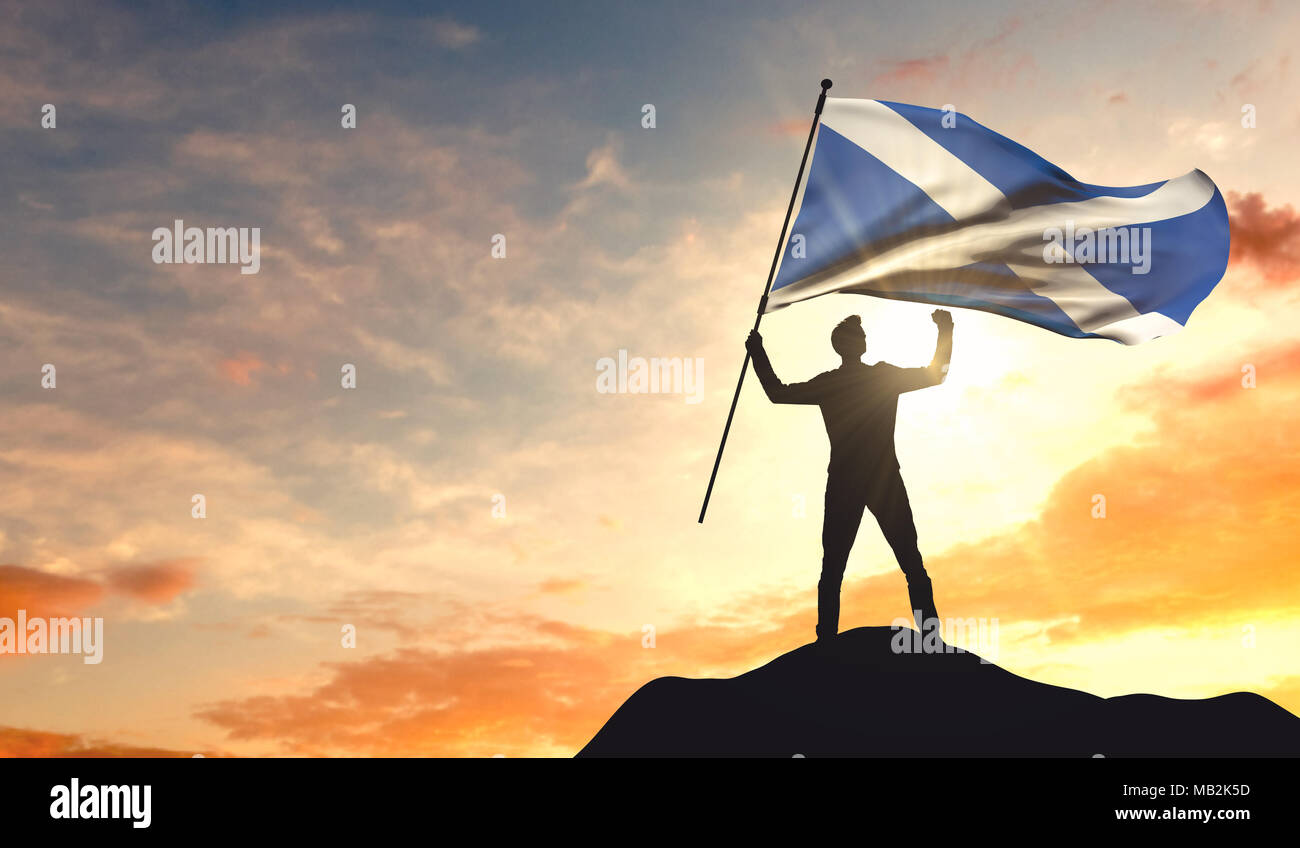 Scotland flag being waved by a man celebrating success at the top of a ...