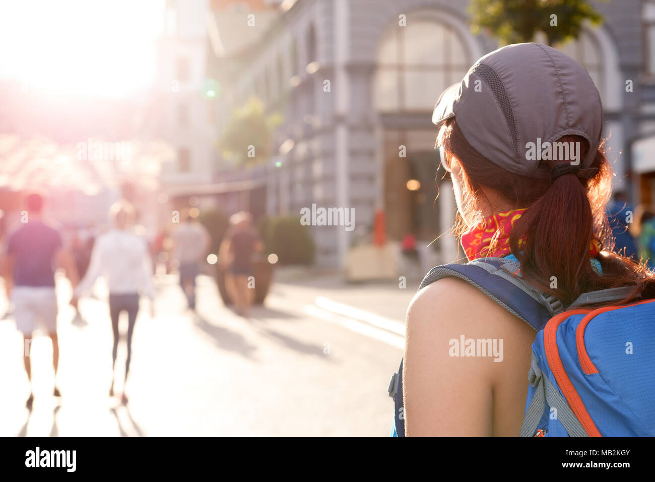 Photo of girl with backpack from behind on blurred background of city ...