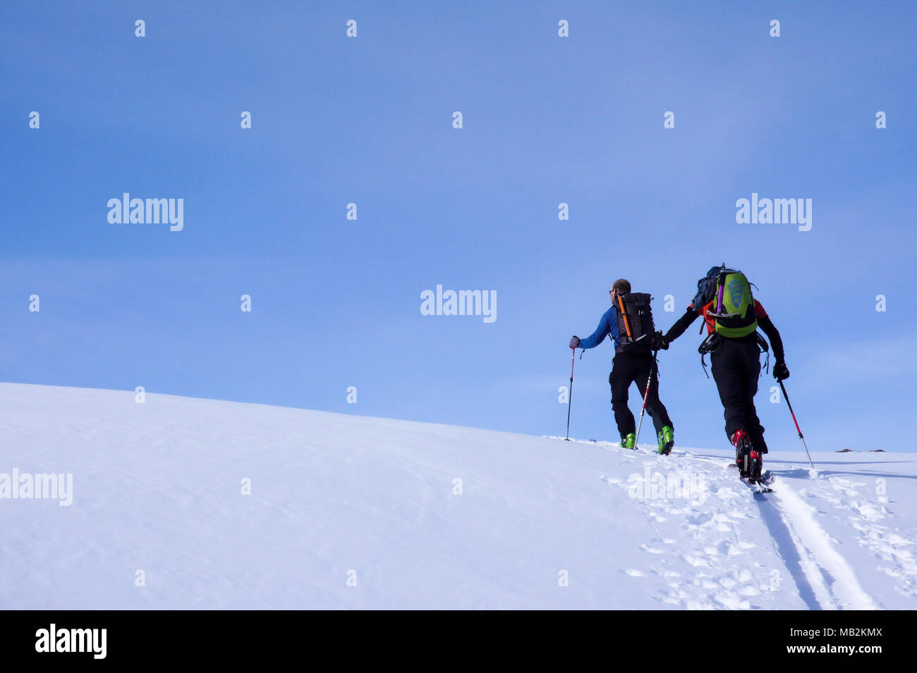 mountain guide on backcountry ski tour leading a client to the peak of ...