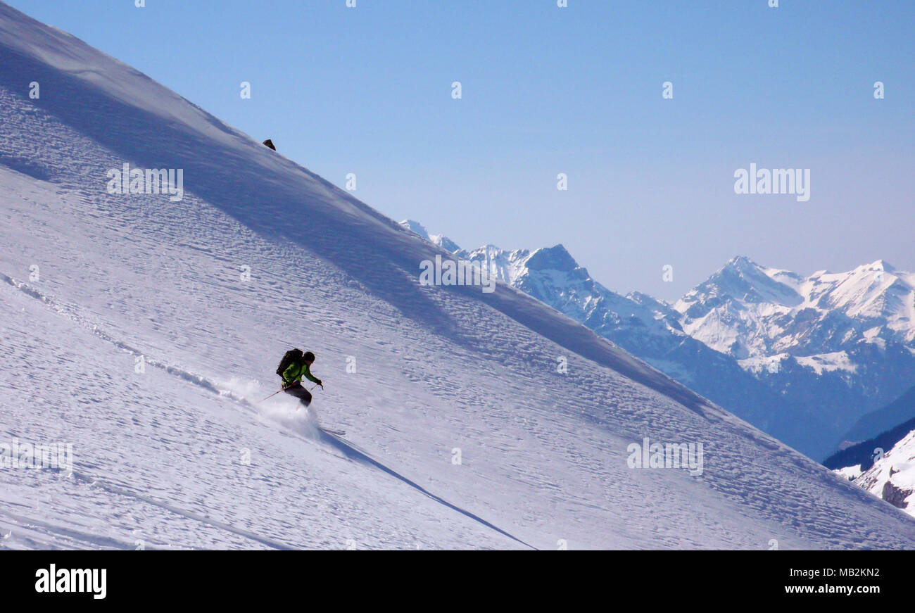 backcountry skier skiing really fast down an untouched mountain side ...