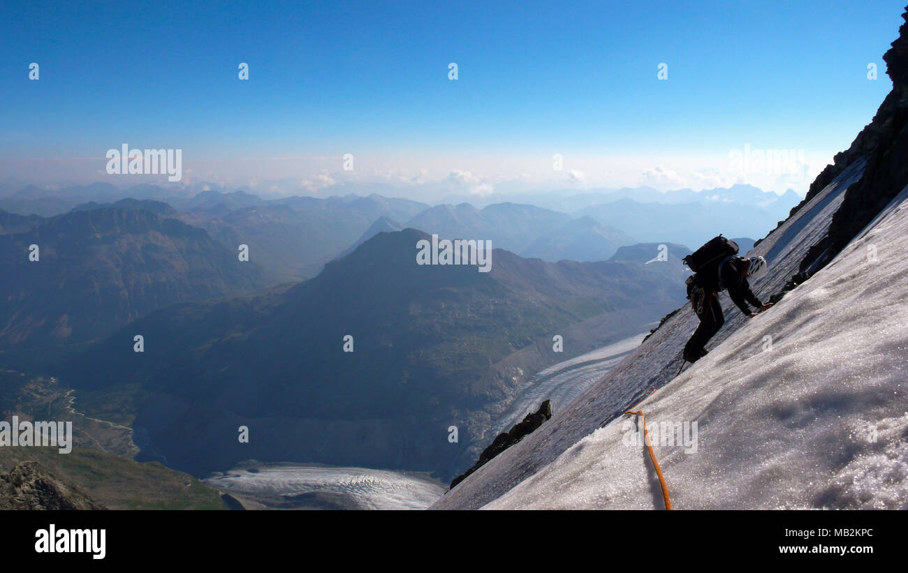 mountain climber traverses a steep and exposed hanging glacier with a ...