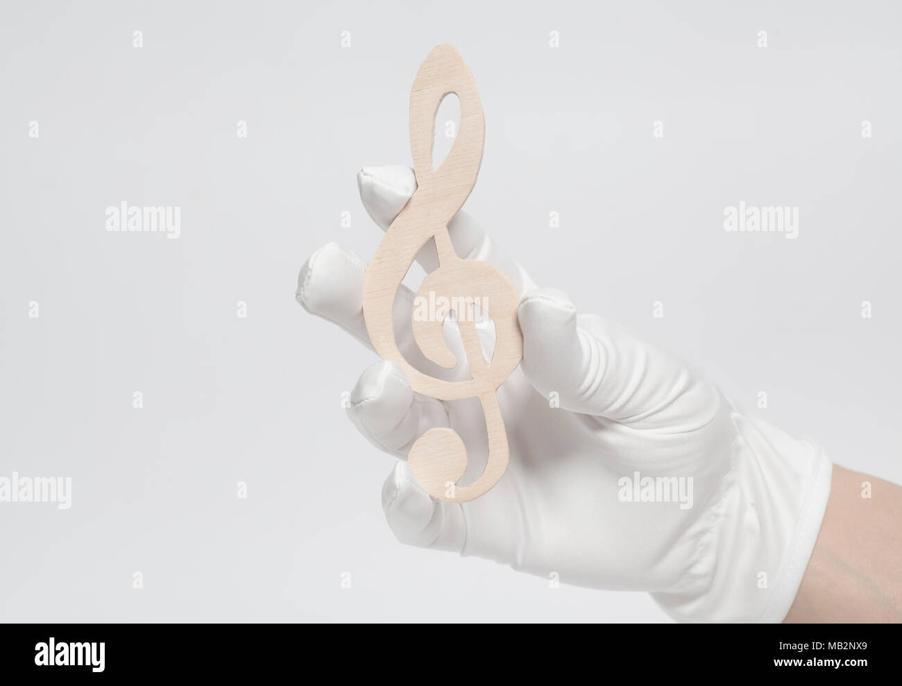 Hand in white glove holding Wooden treble clef sign isolated on white ...