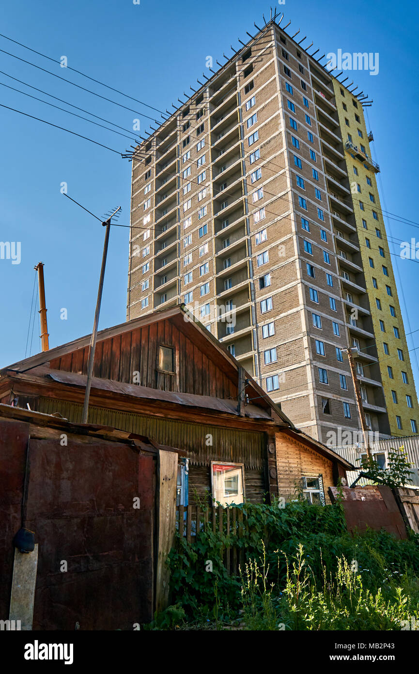 Old wooden house in front of a big tall modern skyscraper representing ...