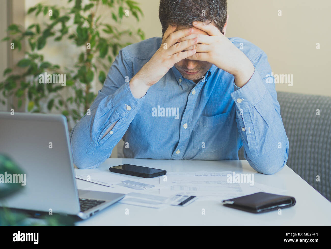 Sad man looking at his monthly bills at home Stock Photo - Alamy