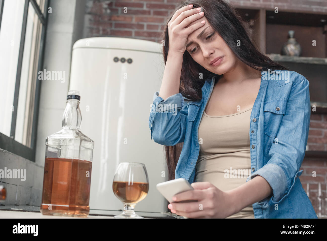 Young female alcoholic social problems standing holding phone looking ...