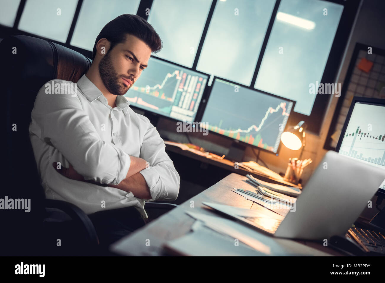 Puzzled man crossed hands and look in computer monitor. Indoor, studio ...