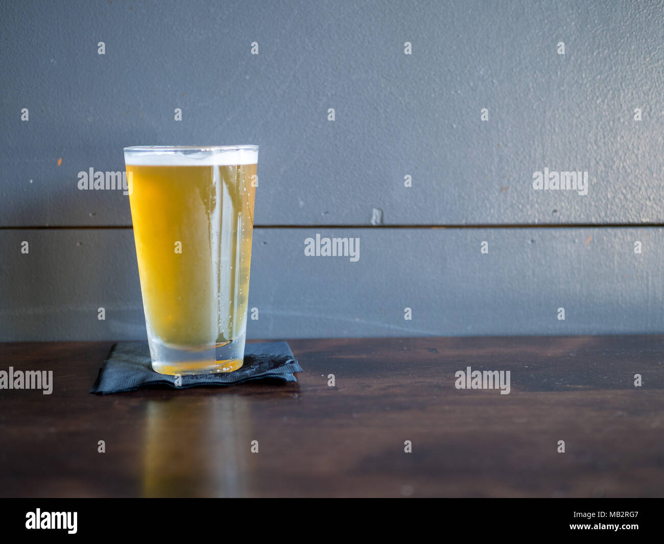 Full glass of beer in a bar next to a wall with light coming from the ...