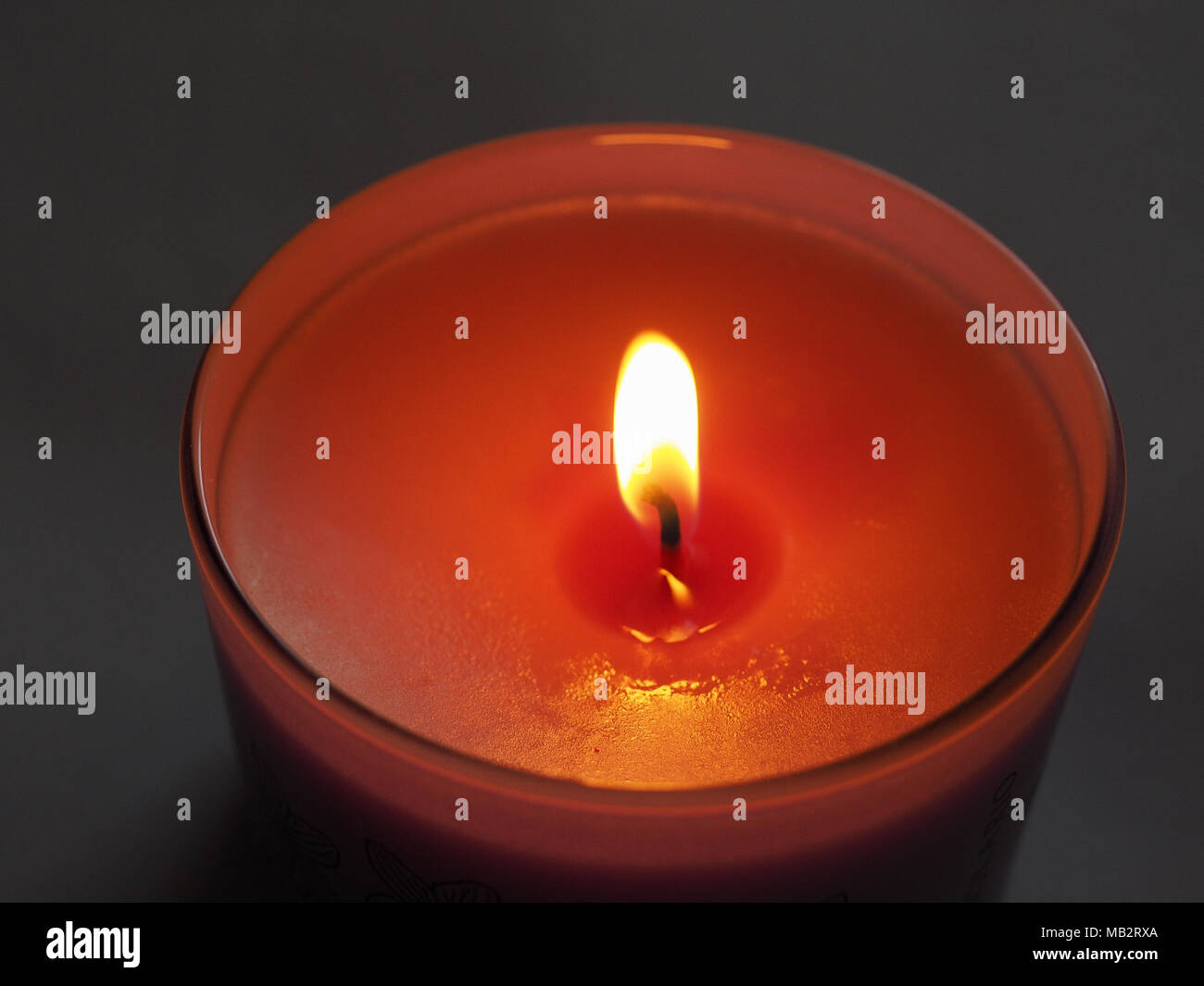 red lit scented candle with flickering flame Stock Photo - Alamy