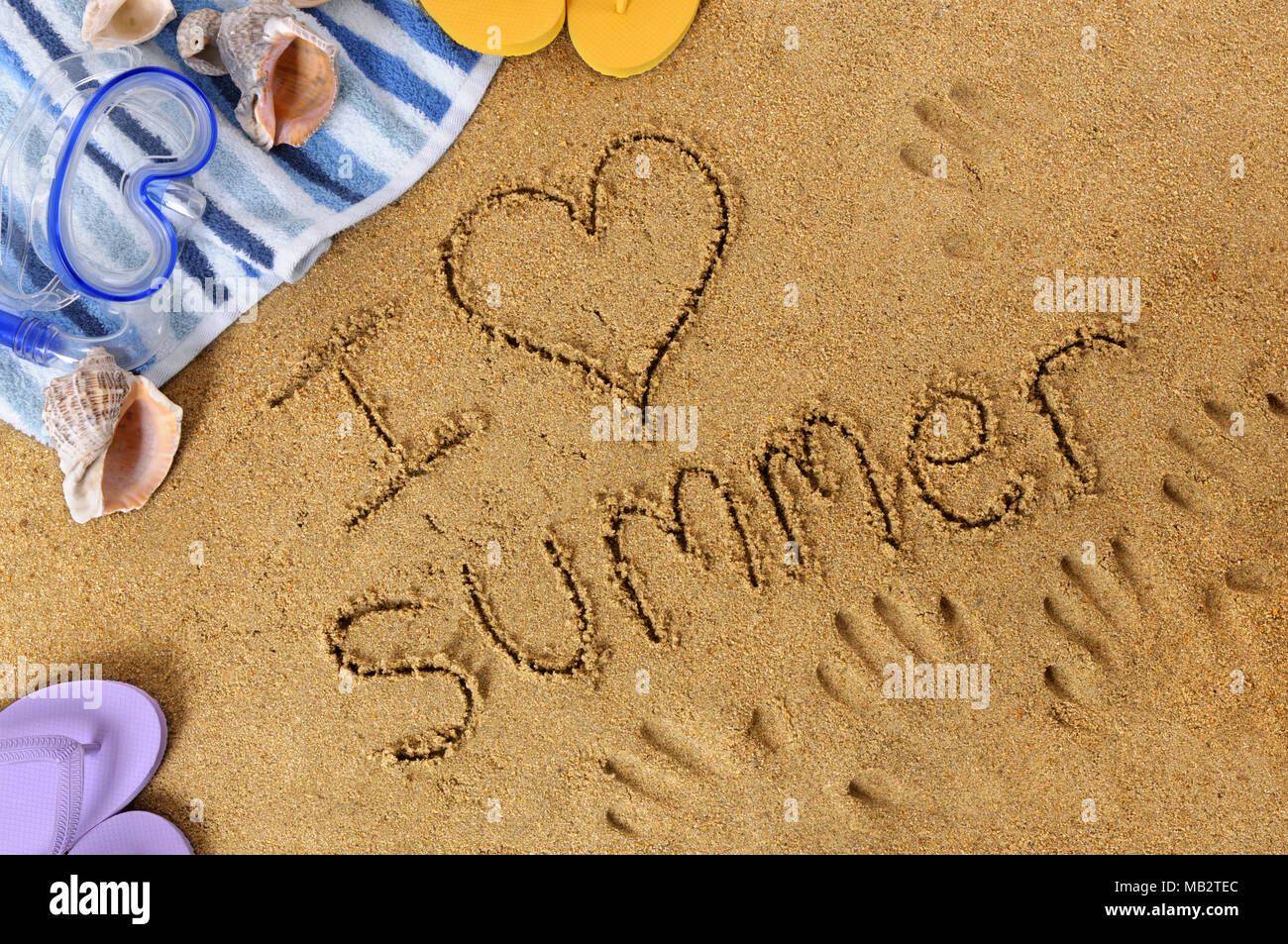 I Love Summer written in sand with handprints, towel, seashells and ...