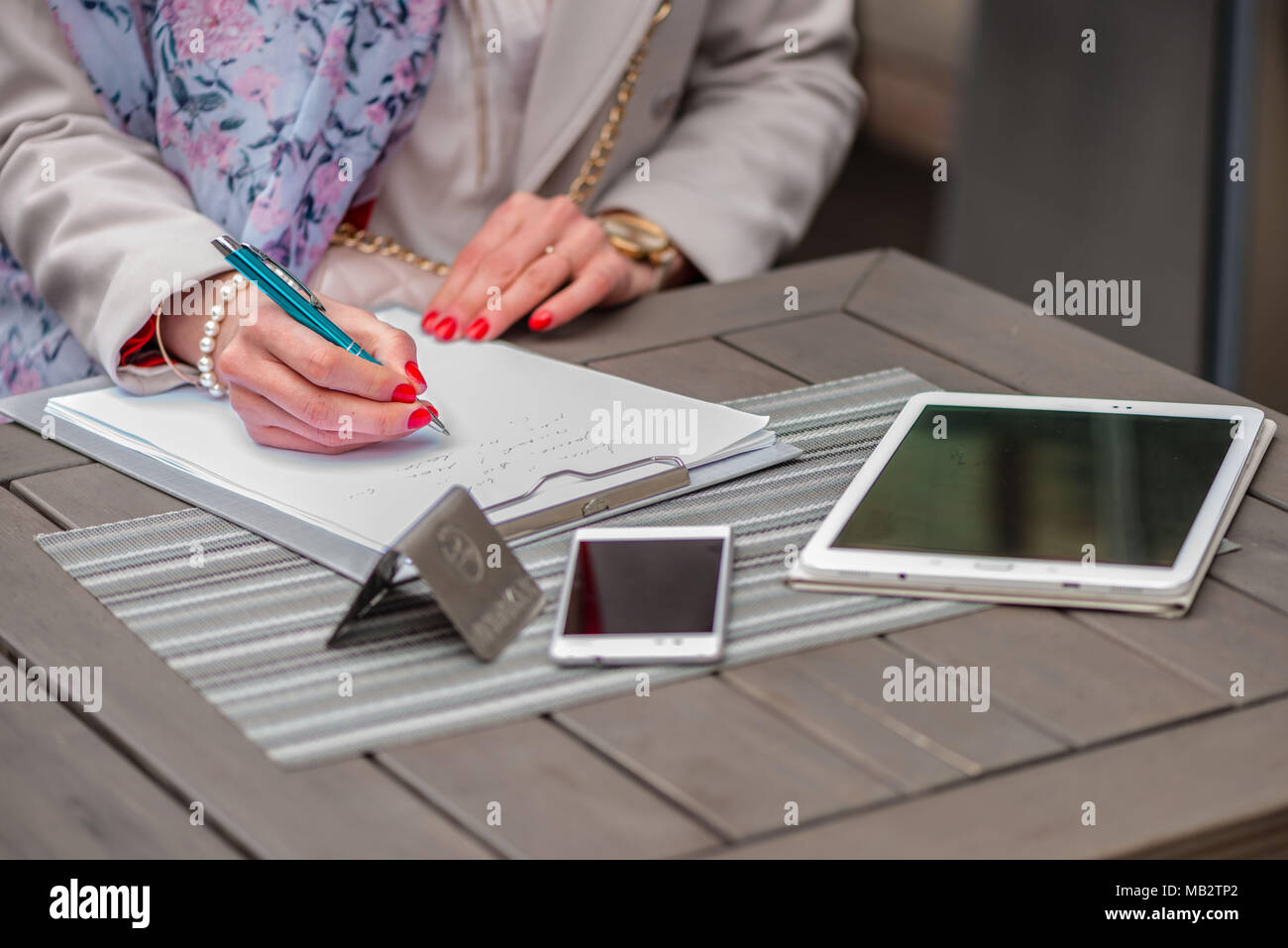 Close-up of female hands. Woman writing something sitting at cafe ...