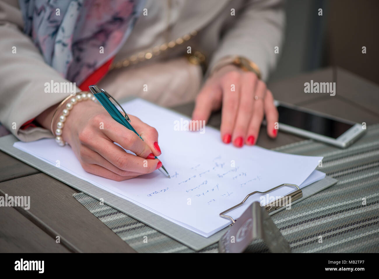 Close-up of female hands. Woman writing something sitting at cafe ...