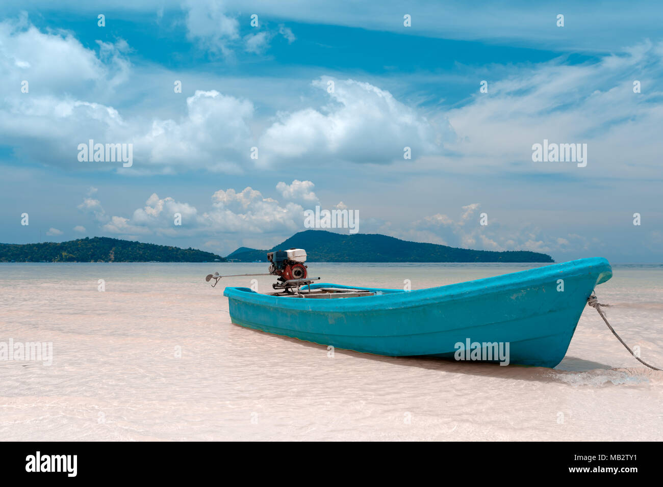 Turquoise motor boat on the beach with engine on the back, clear water ...