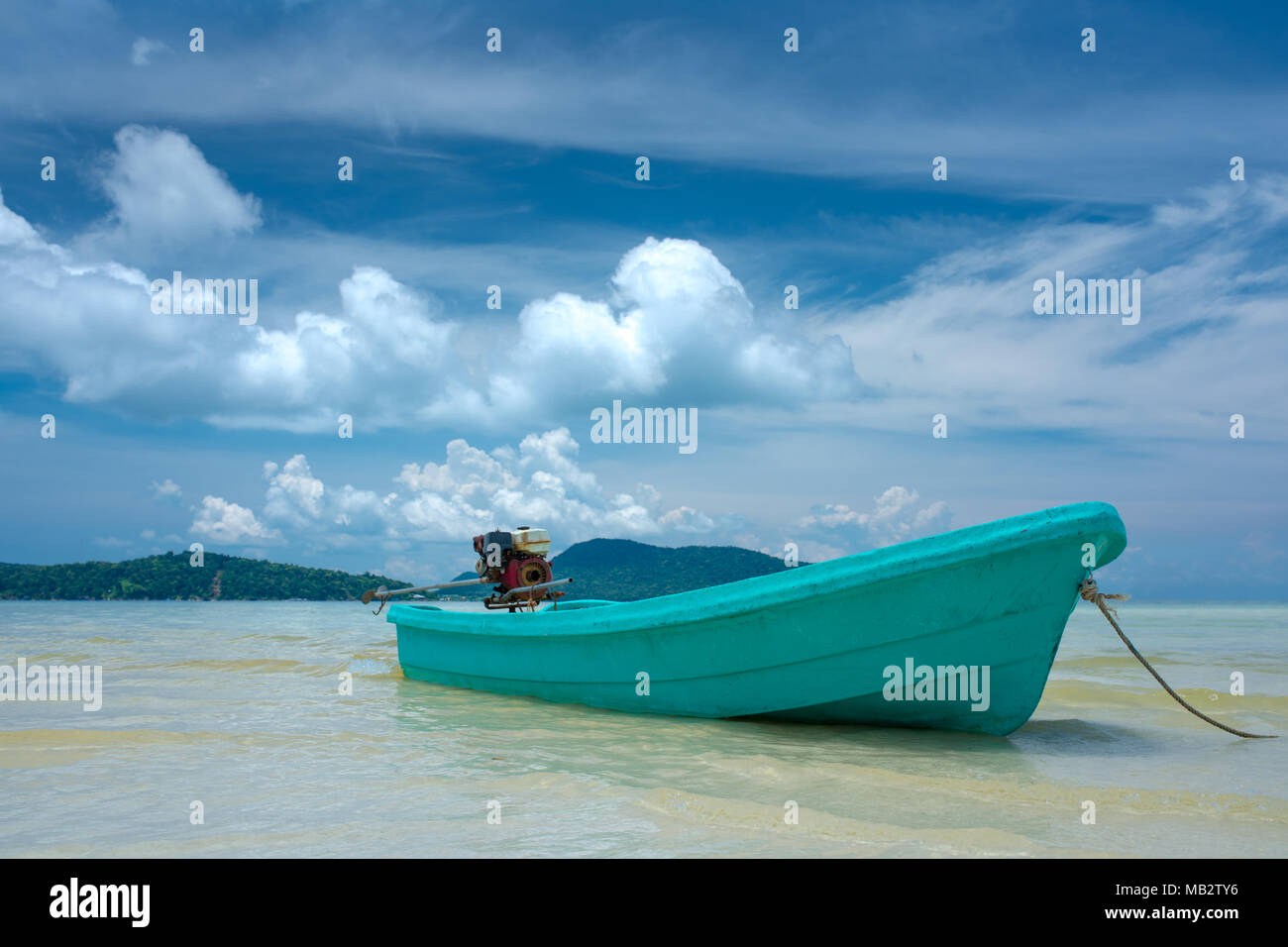 Turquoise motor boat on the beach with engine on the back, clear water ...