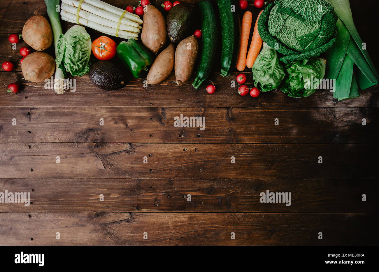 Top view of wooden table with healthy green vegetables arranged in pile ...