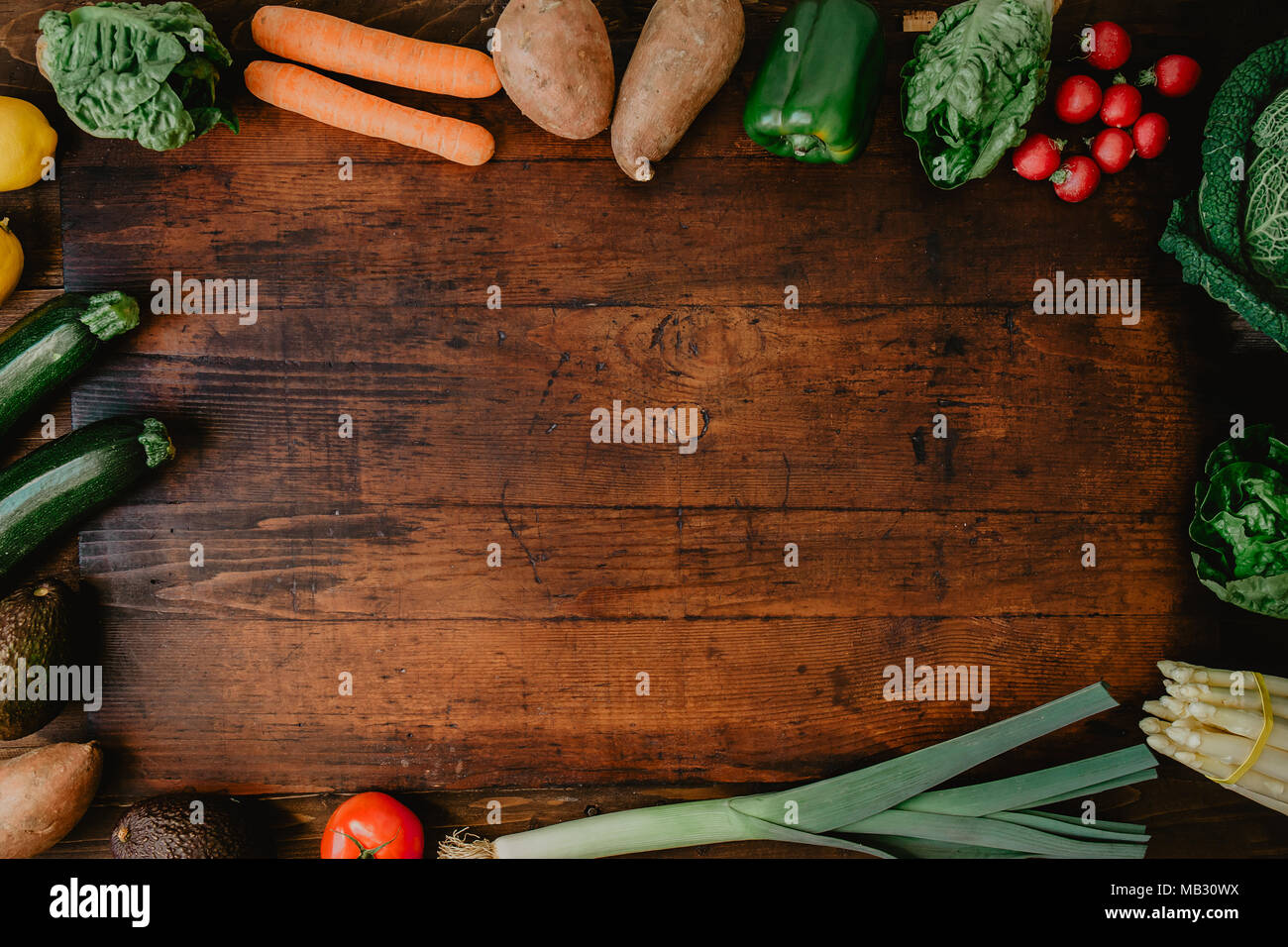Top view of wooden table with healthy green vegetables arranged in pile ...