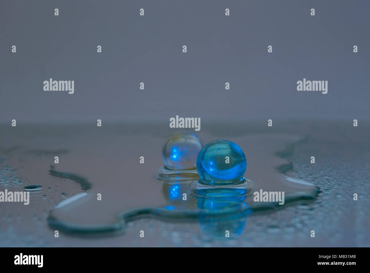 Small glass balls lie in the water. Blue light Stock Photo - Alamy