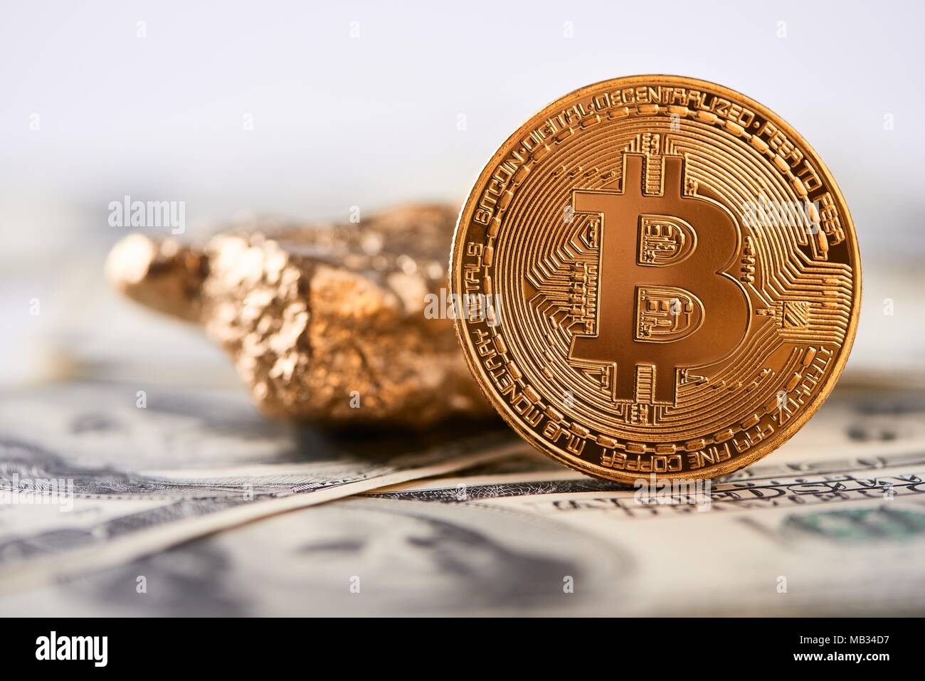 Shiny golden bitcoin and gold lump put on dollar banknote and represent ...