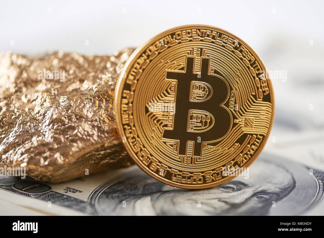 Shiny golden bitcoin and gold lump put on dollar banknote and represent ...