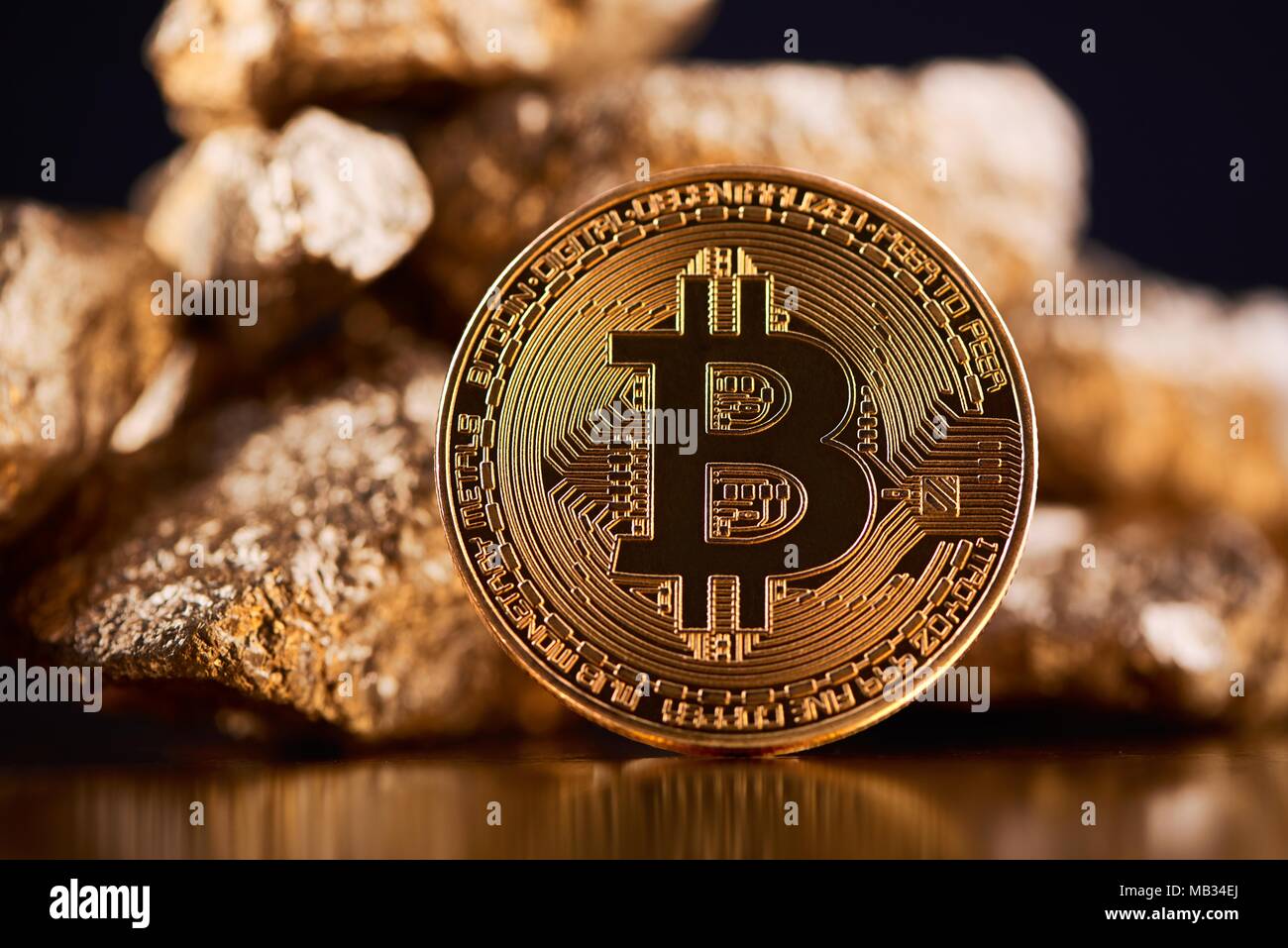 Encrypted golden bitcoin lying in front of blurred gold lumps being ...