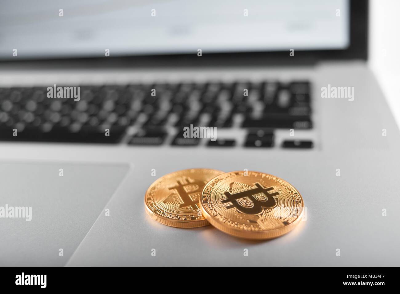 Two golden bitcoins as main cryptocurrencies placed on silver laptop ...