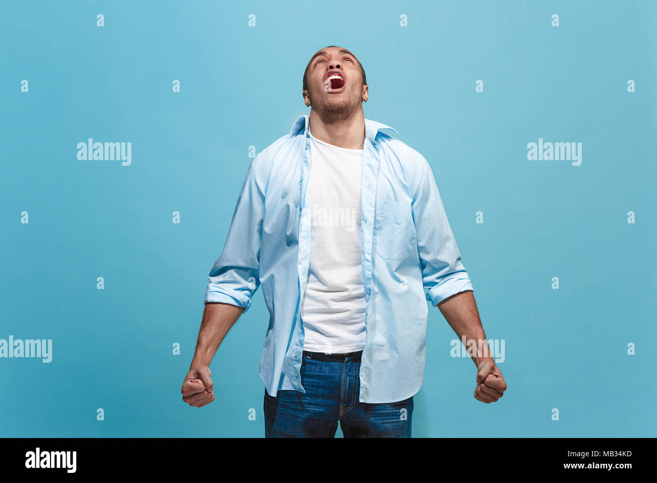 The young emotional angry man screaming on blue studio background Stock ...