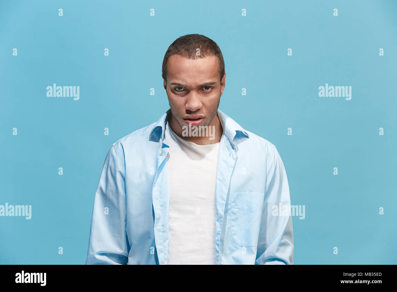 The young emotional angry man on blue studio background Stock Photo - Alamy