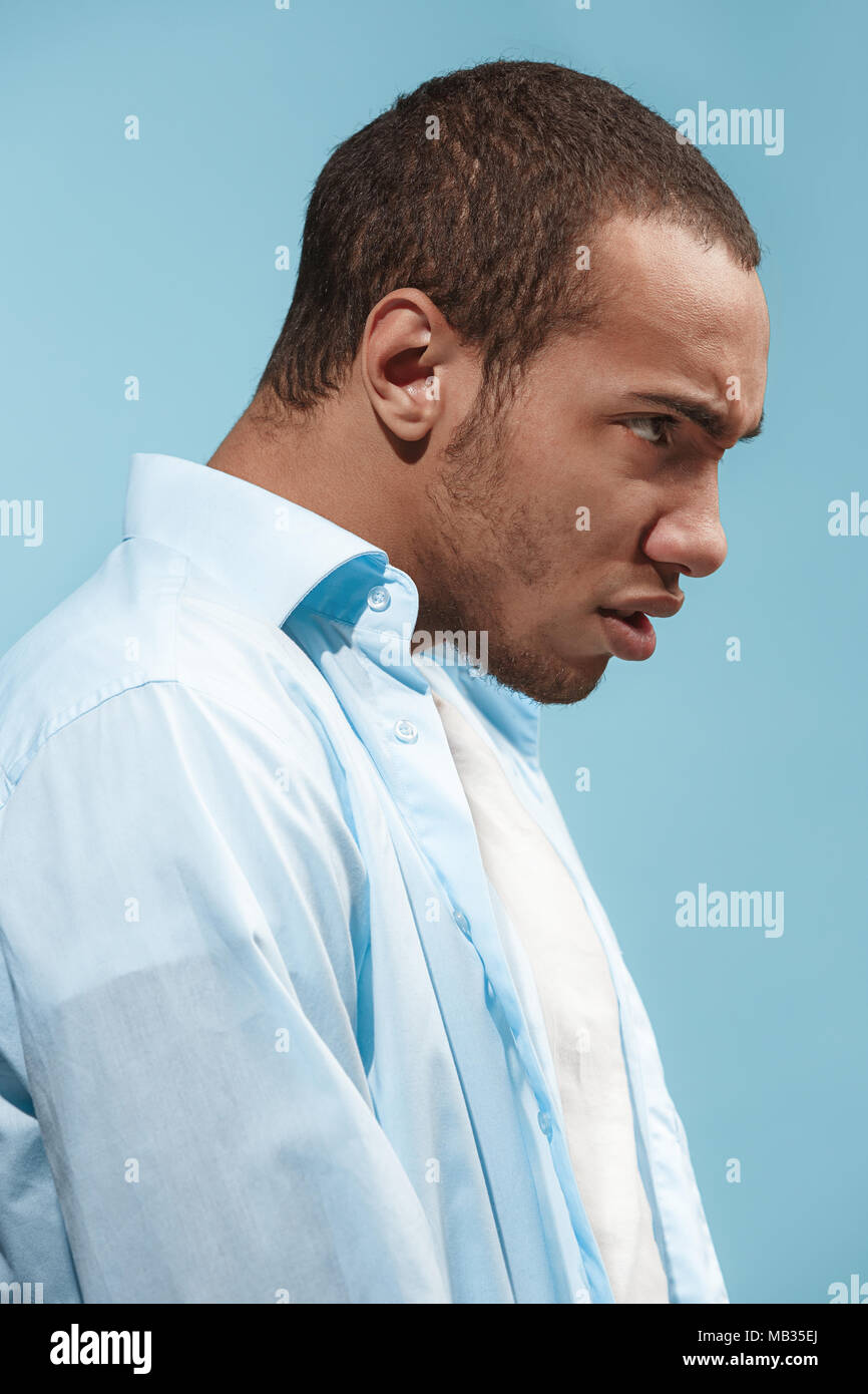 The young emotional angry man on blue studio background Stock Photo - Alamy