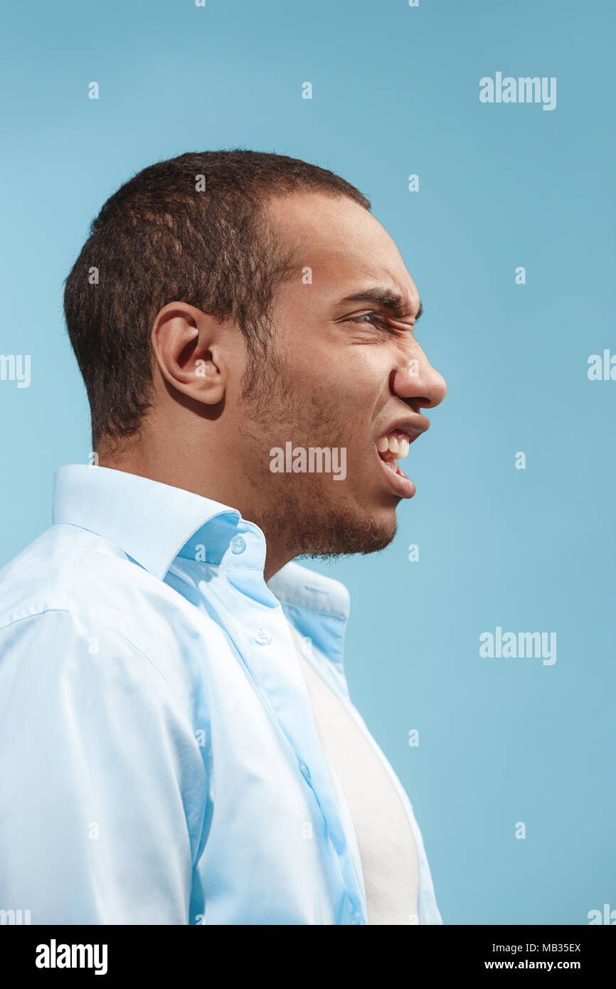 The young emotional angry man on blue studio background Stock Photo - Alamy