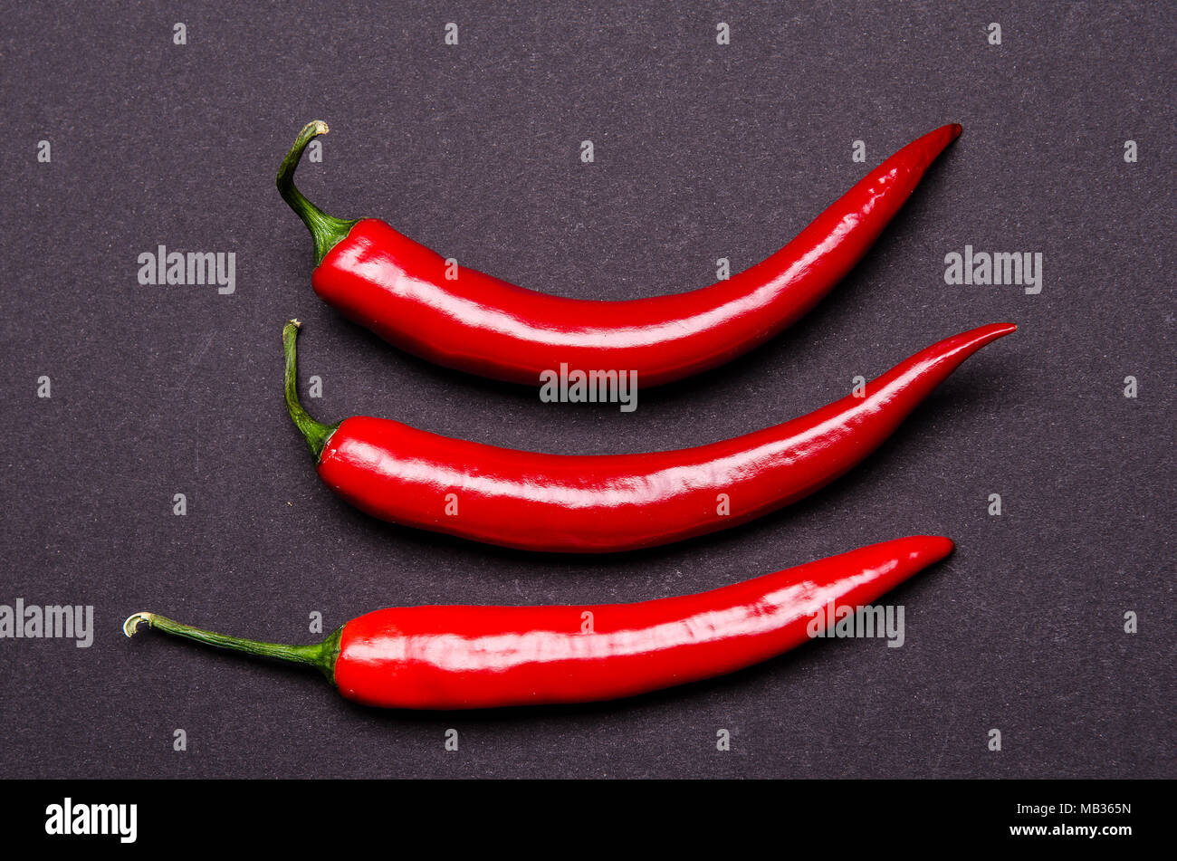 three chilies on a grey background, isolated Stock Photo - Alamy