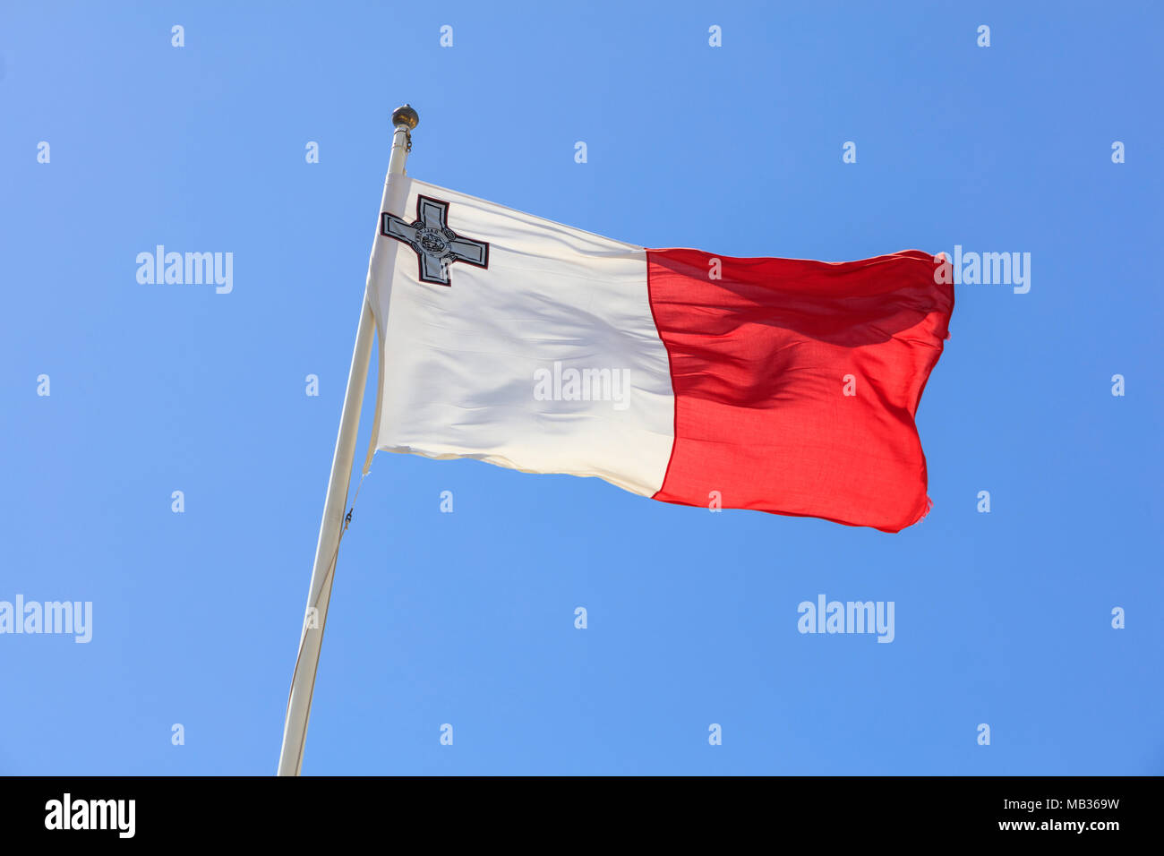 Malta flag. Malta flag on a flagpole waving on a bright blue sky ...