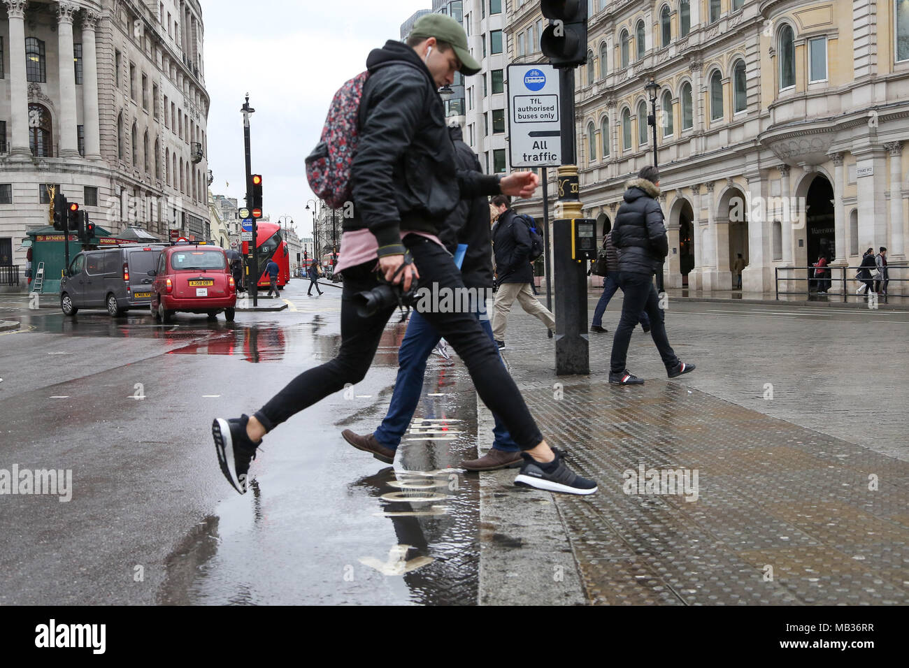 Tourists shelter from the rain beneath umbrellas in Trafalgar Square as ...