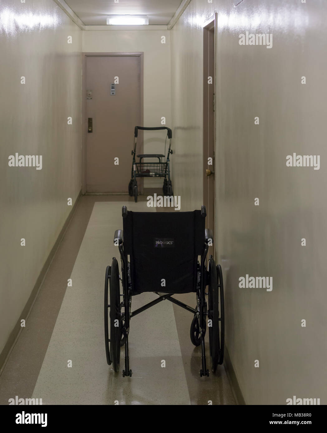 A walker and a wheelchair in a hallway outside apartment doors in the ...
