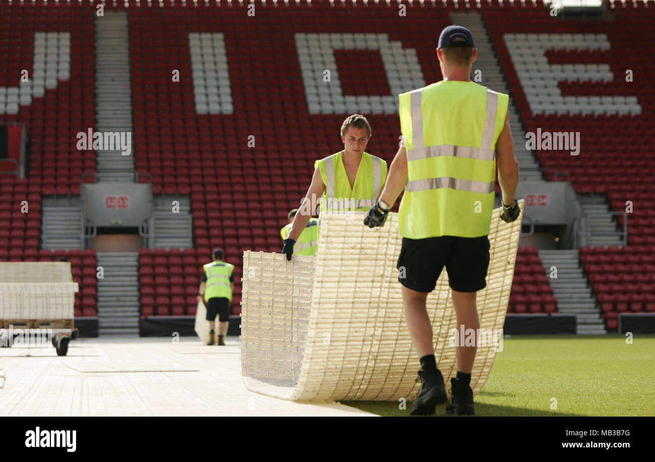 Workers lay a temporary plastic flooring over a football pitch to ...