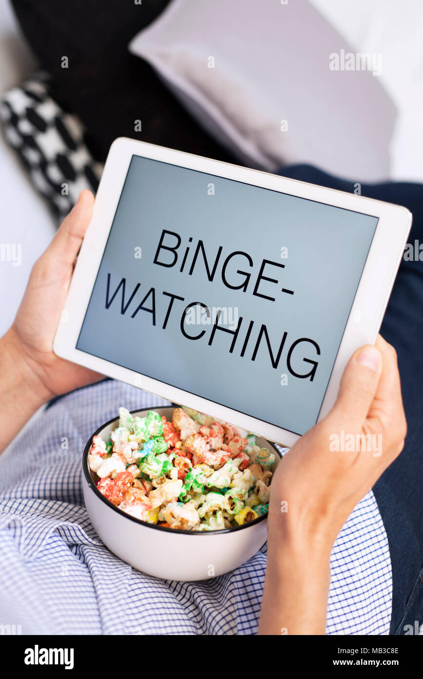 closeup of a young caucasian man lying comfortably on a couch, eating ...