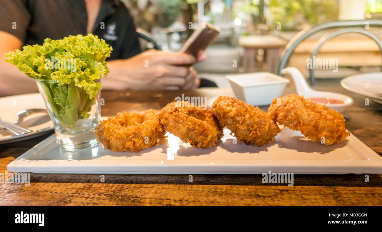 Thai fried fish patty with man using smart phone Stock Photo - Alamy