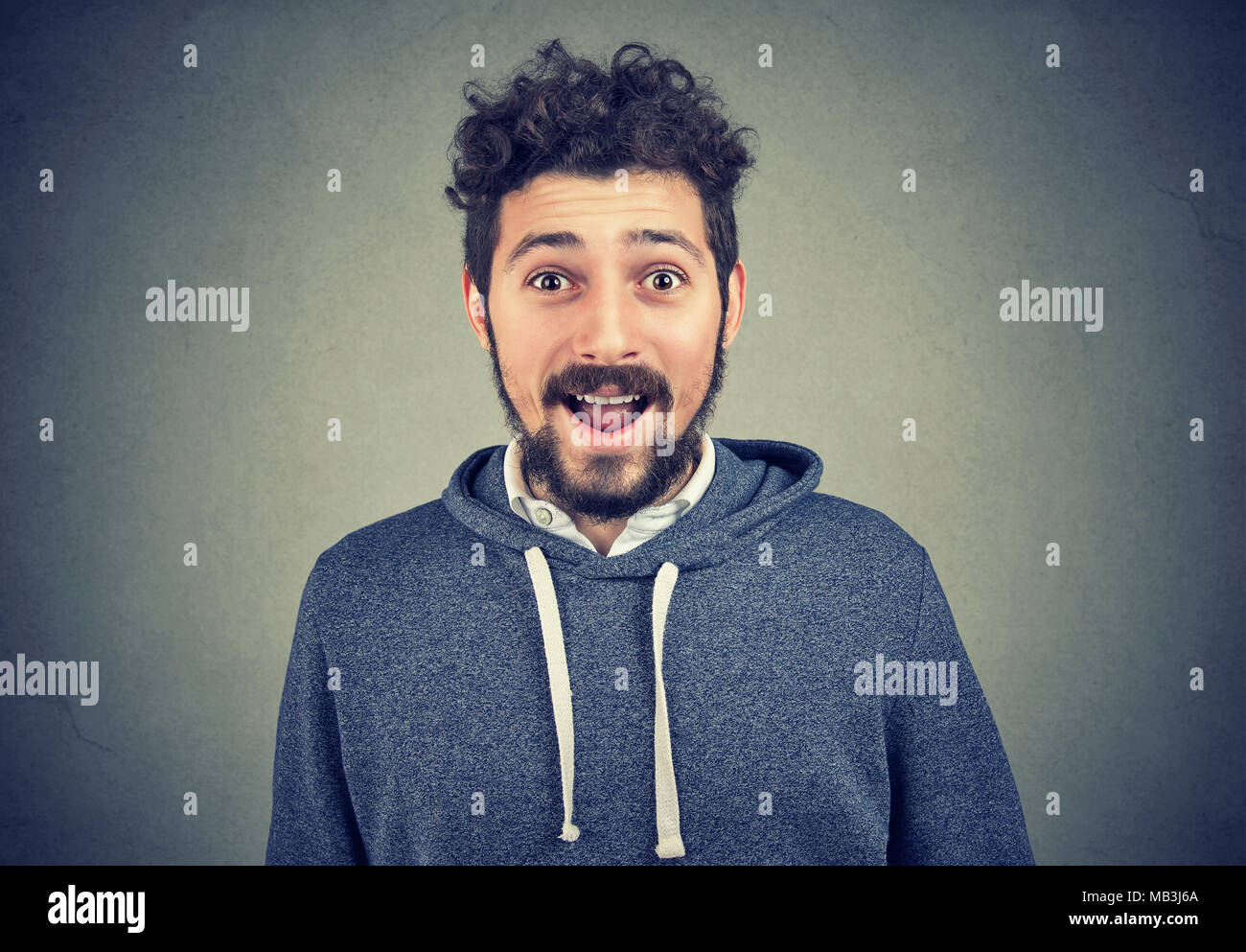 Young man posing confidently with big smile and surprise on gray ...