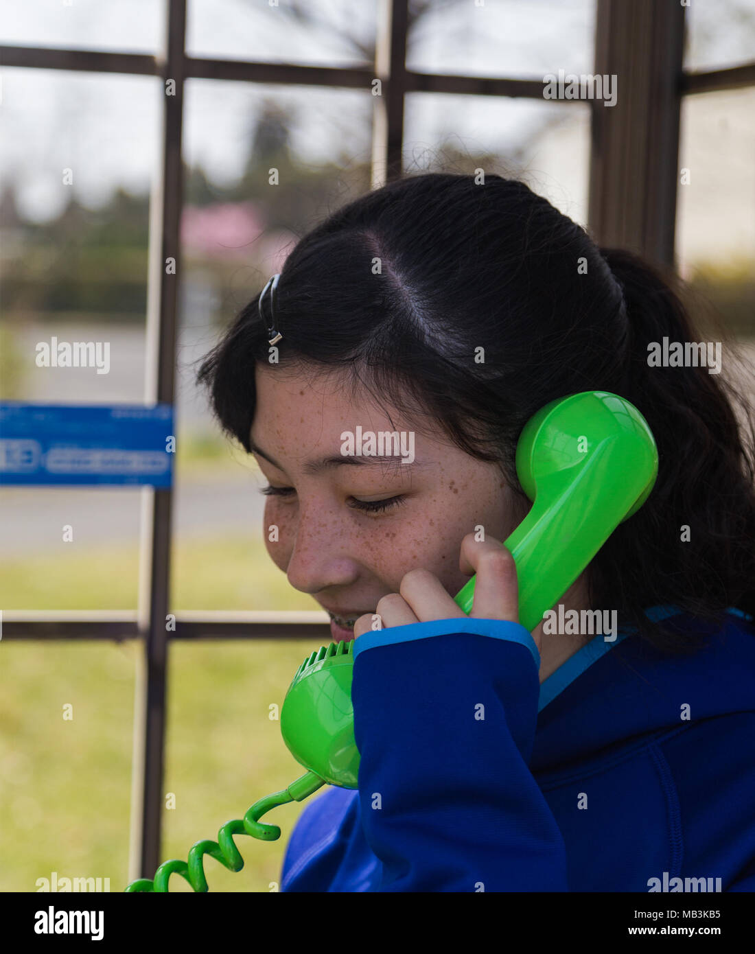 Teenage girl talking on phone in phone booth Stock Photo - Alamy