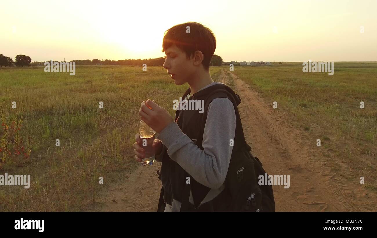 Boy teenager tourist drinking water from a plastic bottle in nature ...