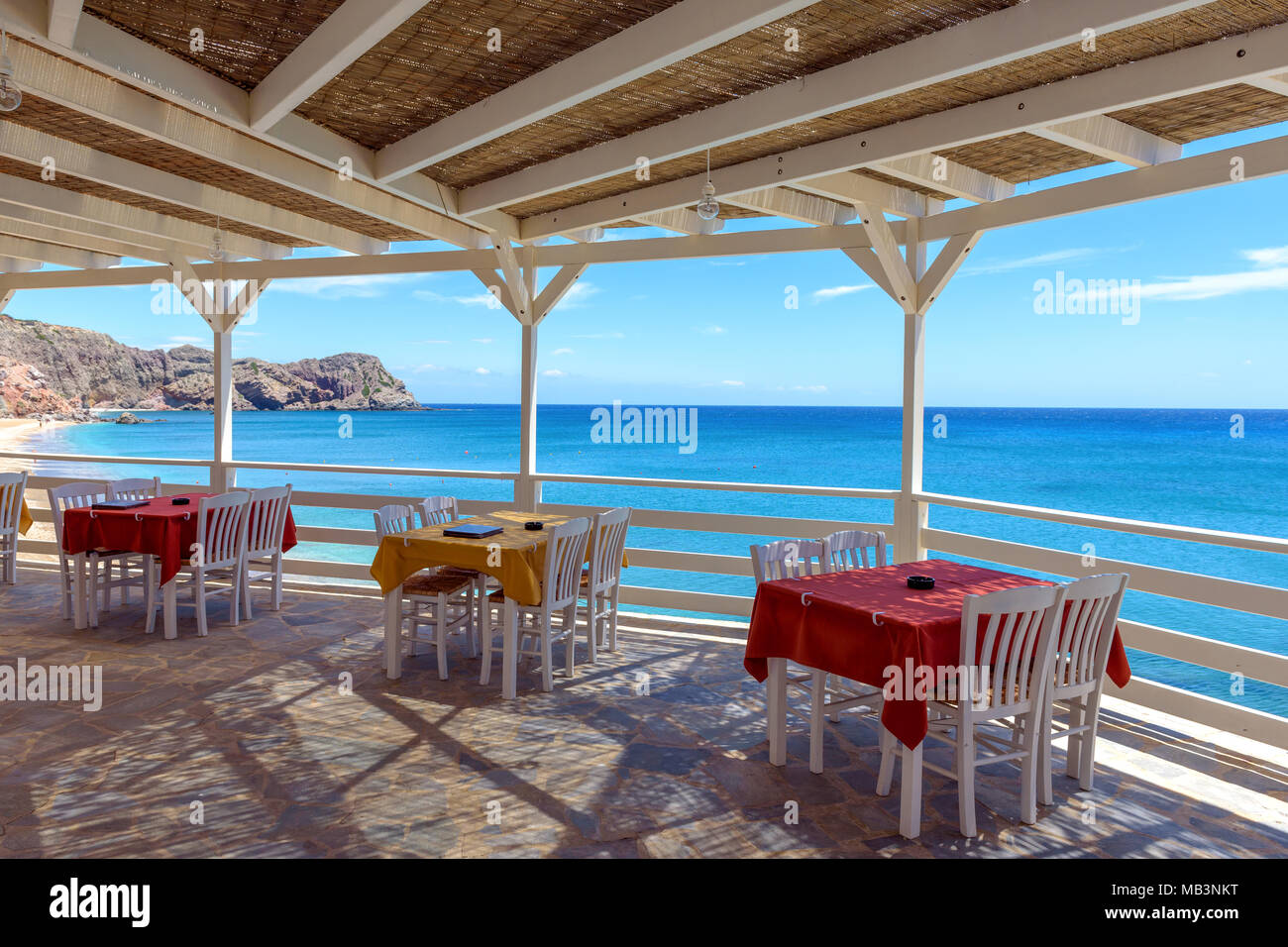 Tables and chairs in typical Greek tavern with view of Aegean Sea ...