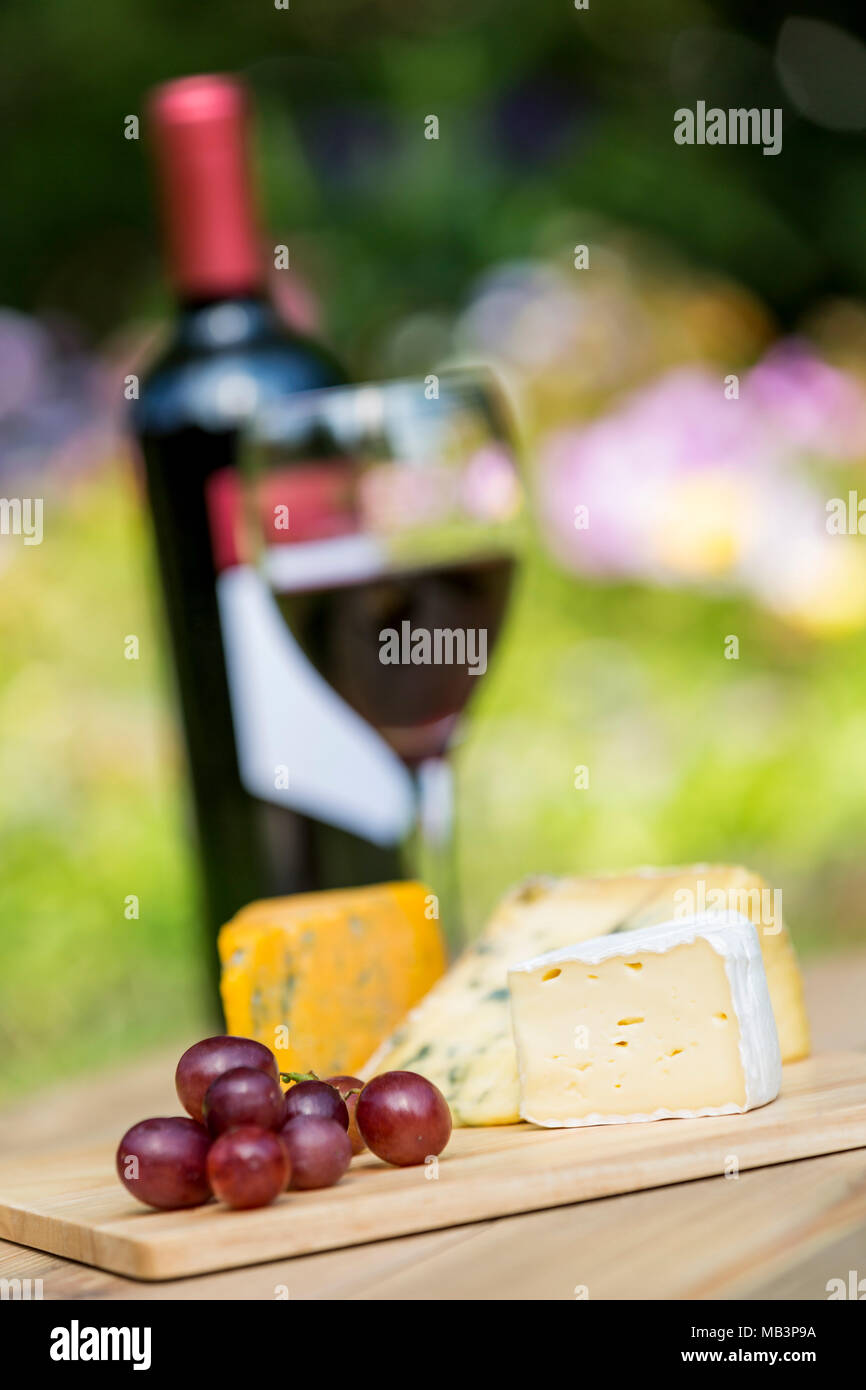 Selection of red and green grapes with cheese platter on wooden serving ...