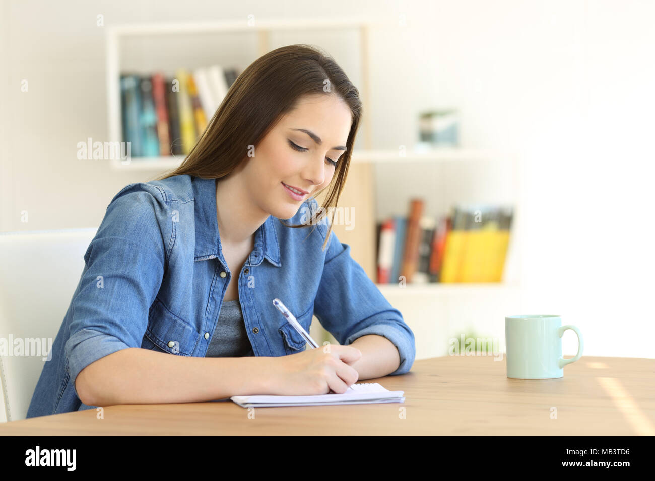Relaxed girl writing in a notebook on a table at home Stock Photo - Alamy